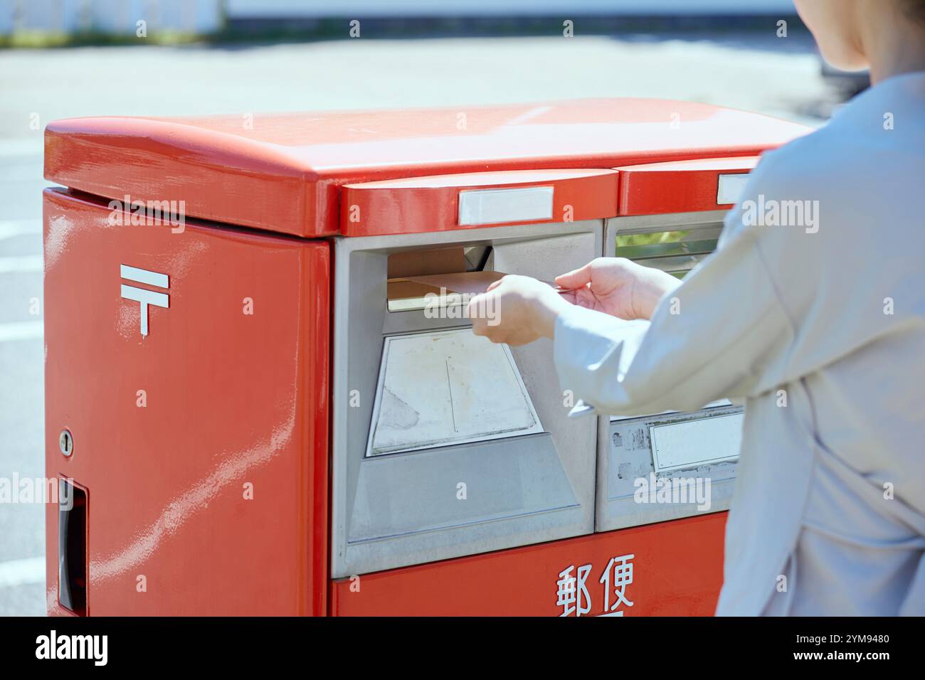 Young woman's hand putting an envelope in a mailbox Stock Photo - Alamy