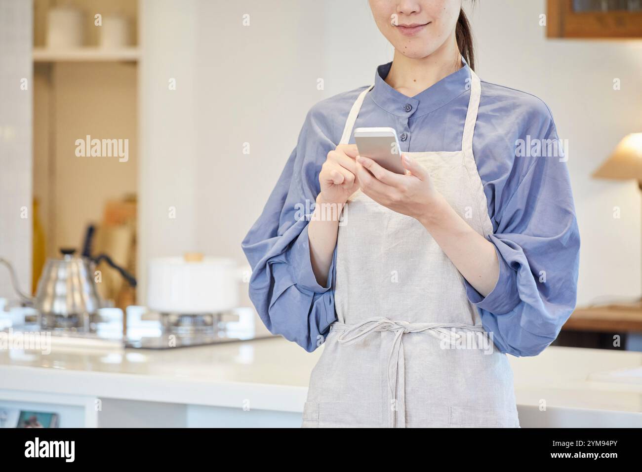 Young woman controlling home appliances with a smartphone Stock Photo ...