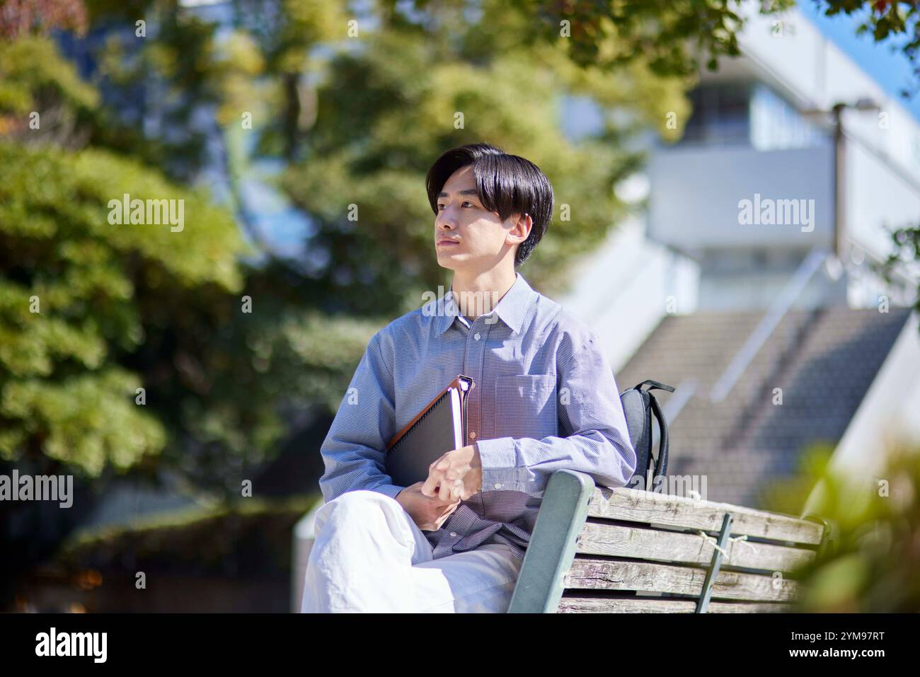 Japanese university student man sitting on a bench on a university ...