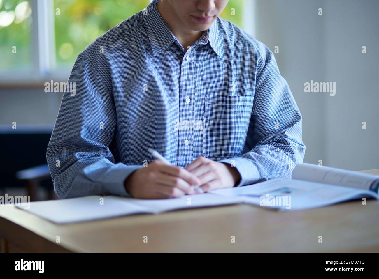 A male Japanese university student studying in the living room of his ...
