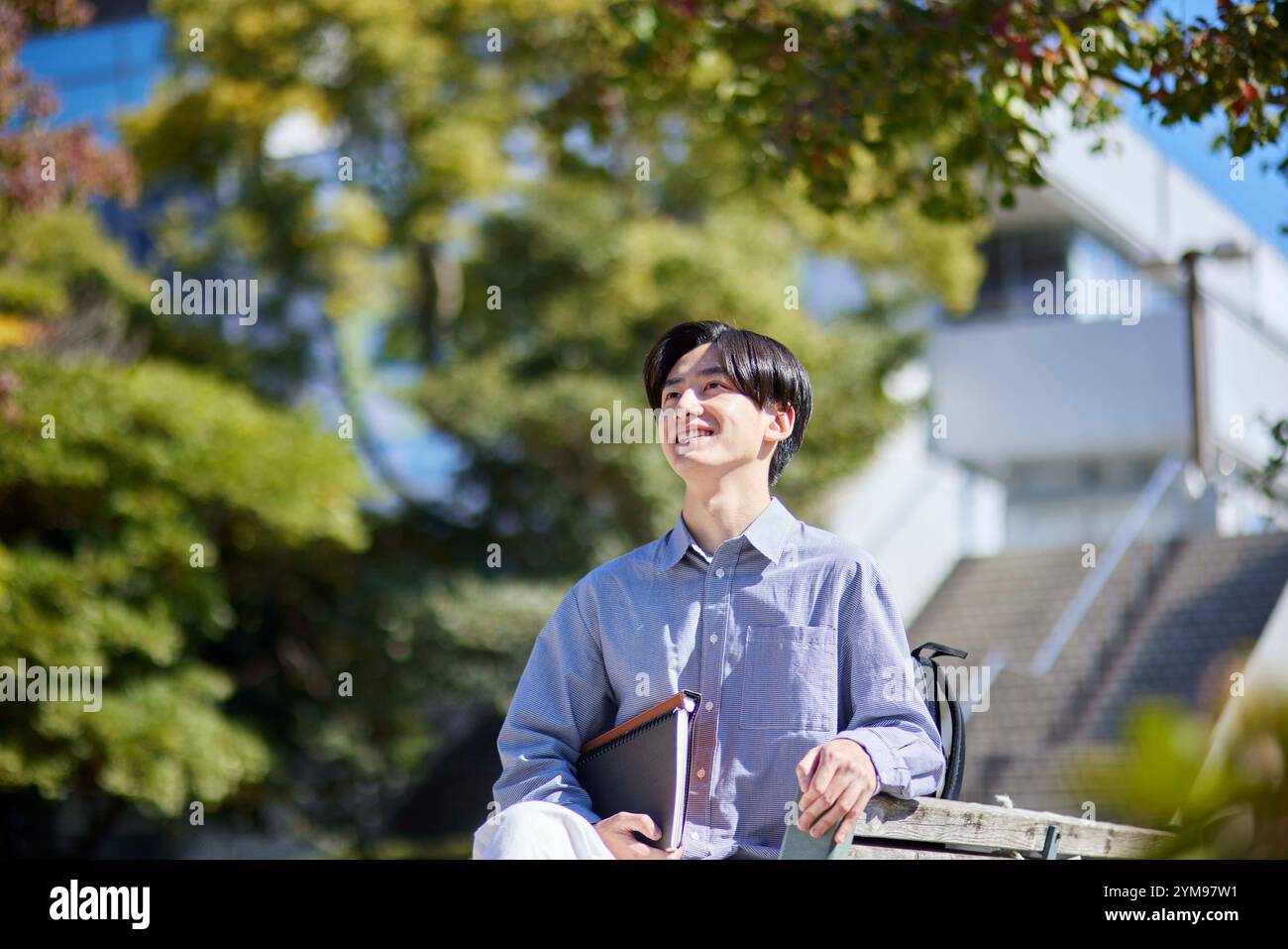 Japanese university student man sitting on a bench on a university ...
