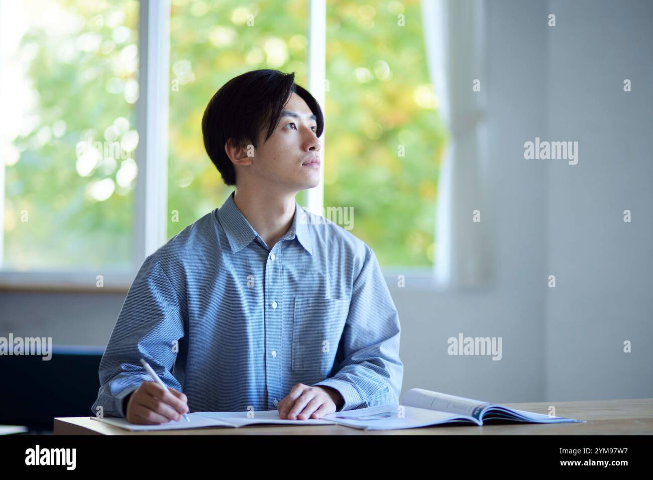 A male Japanese university student studying in the living room of his ...