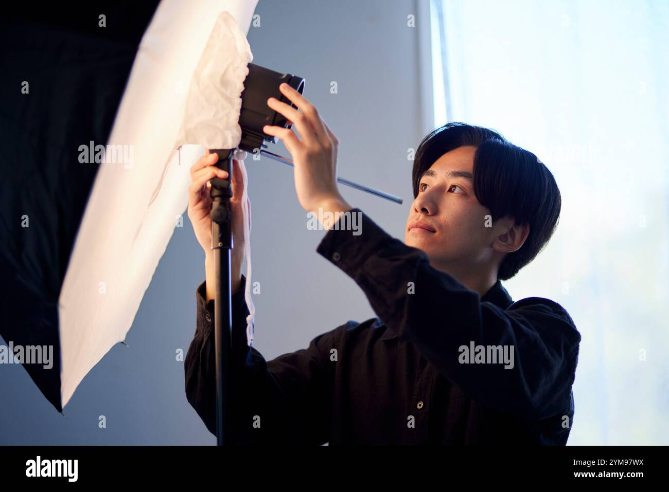 A Japanese male photographer adjusting the strobe in a photography ...