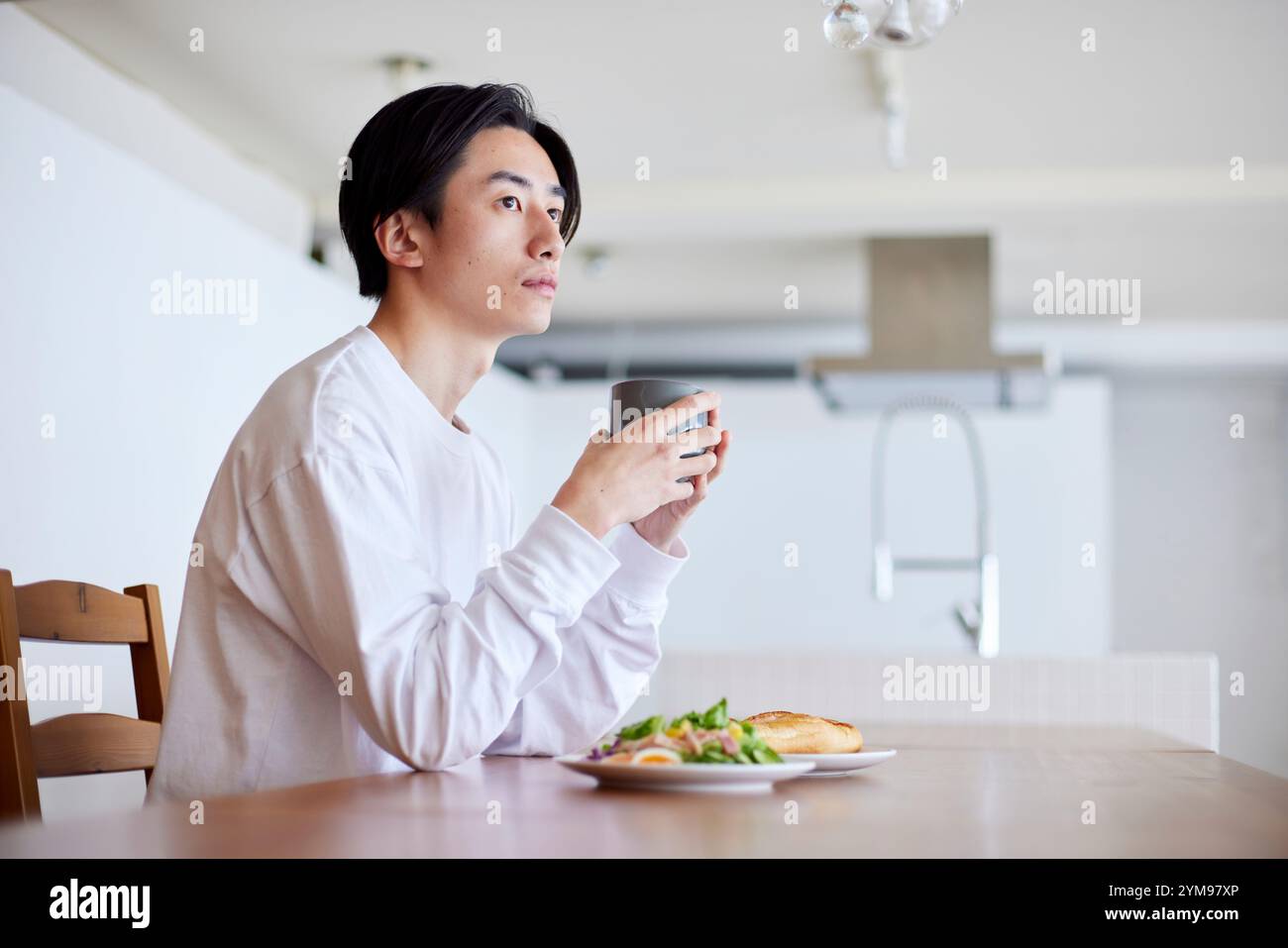 Young Japanese man eating breakfast in the living room Stock Photo - Alamy