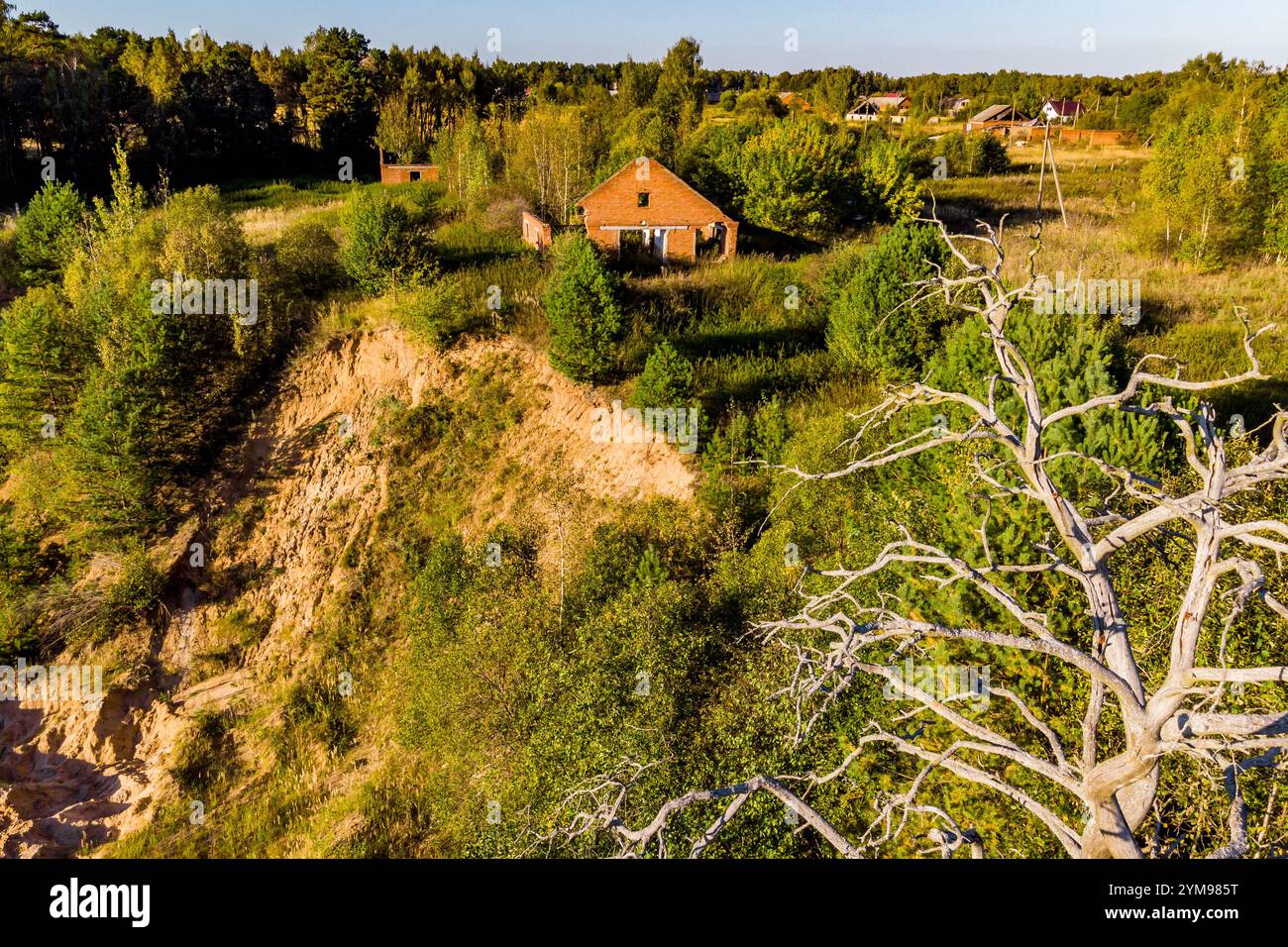 Withered tree and ruins of buildings on the edge of a cliff, abandoned ...