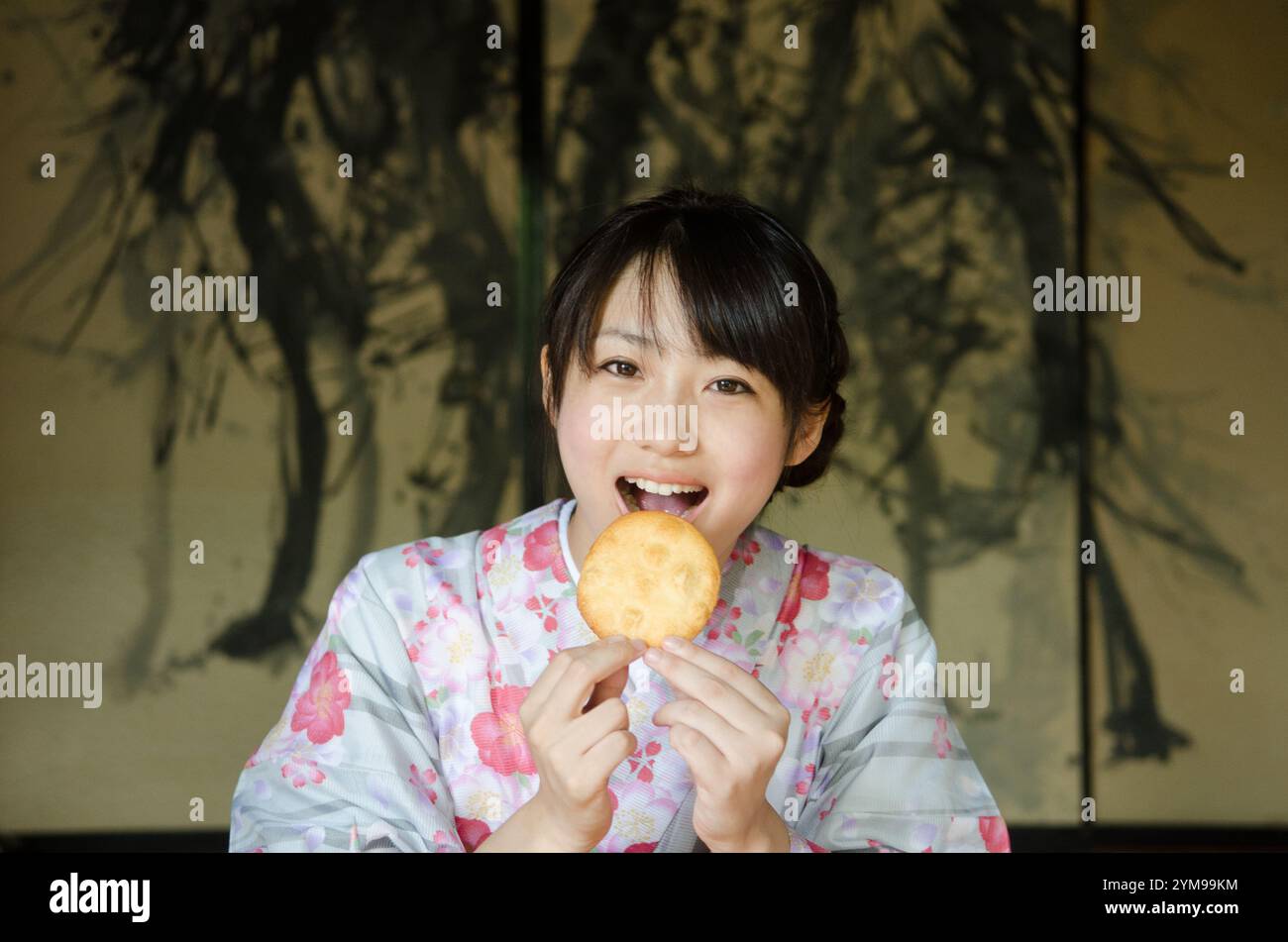 Woman in kimono eating rice cracker Stock Photo - Alamy