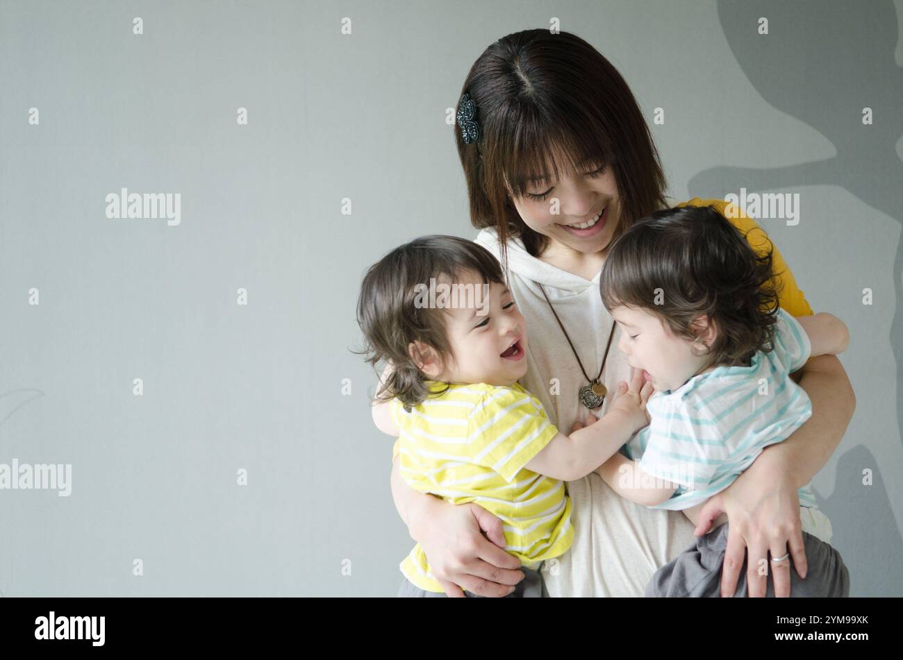 Woman carrying twins in her arms Stock Photo - Alamy
