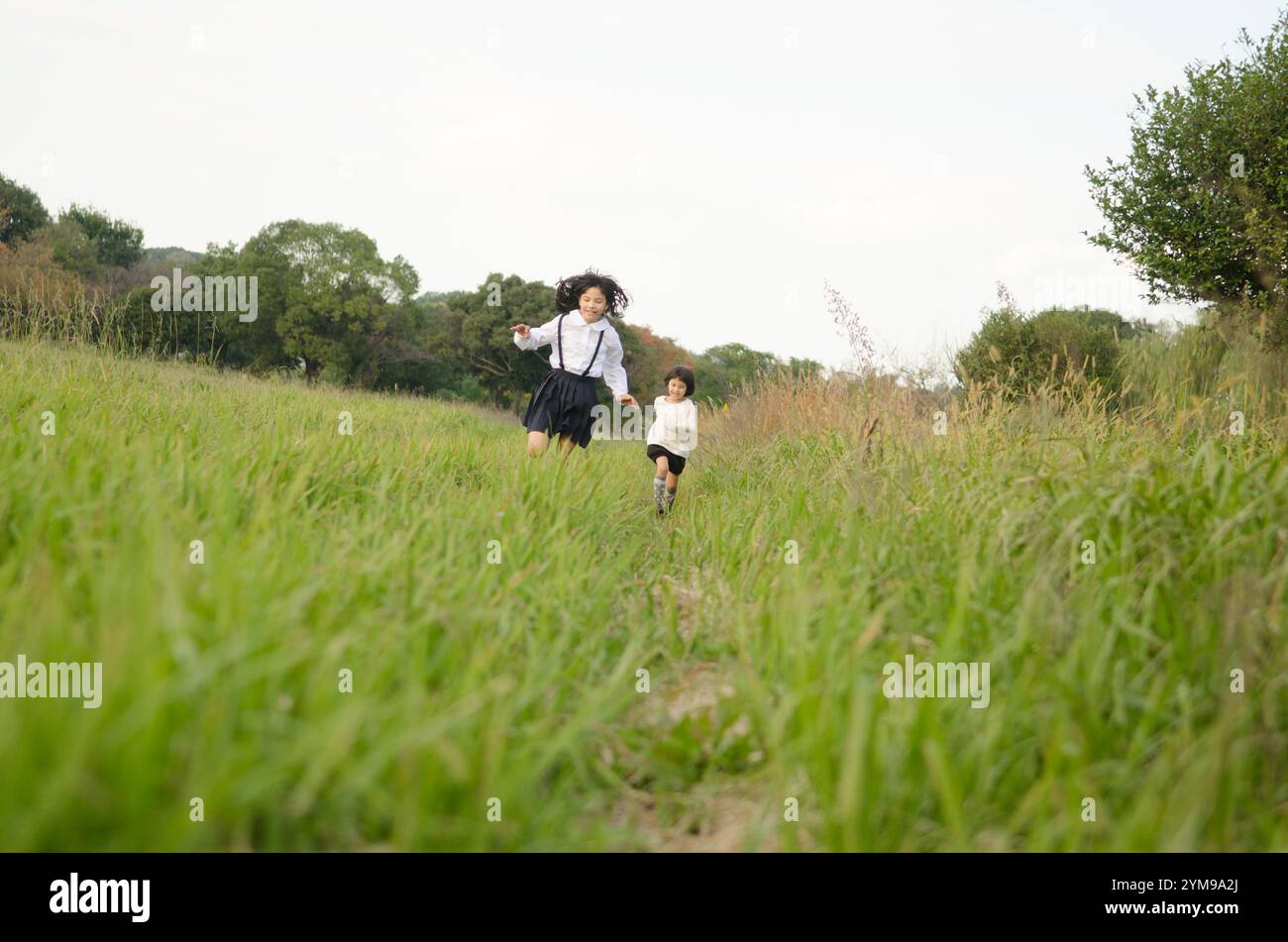 Sisters running in grass Stock Photo - Alamy