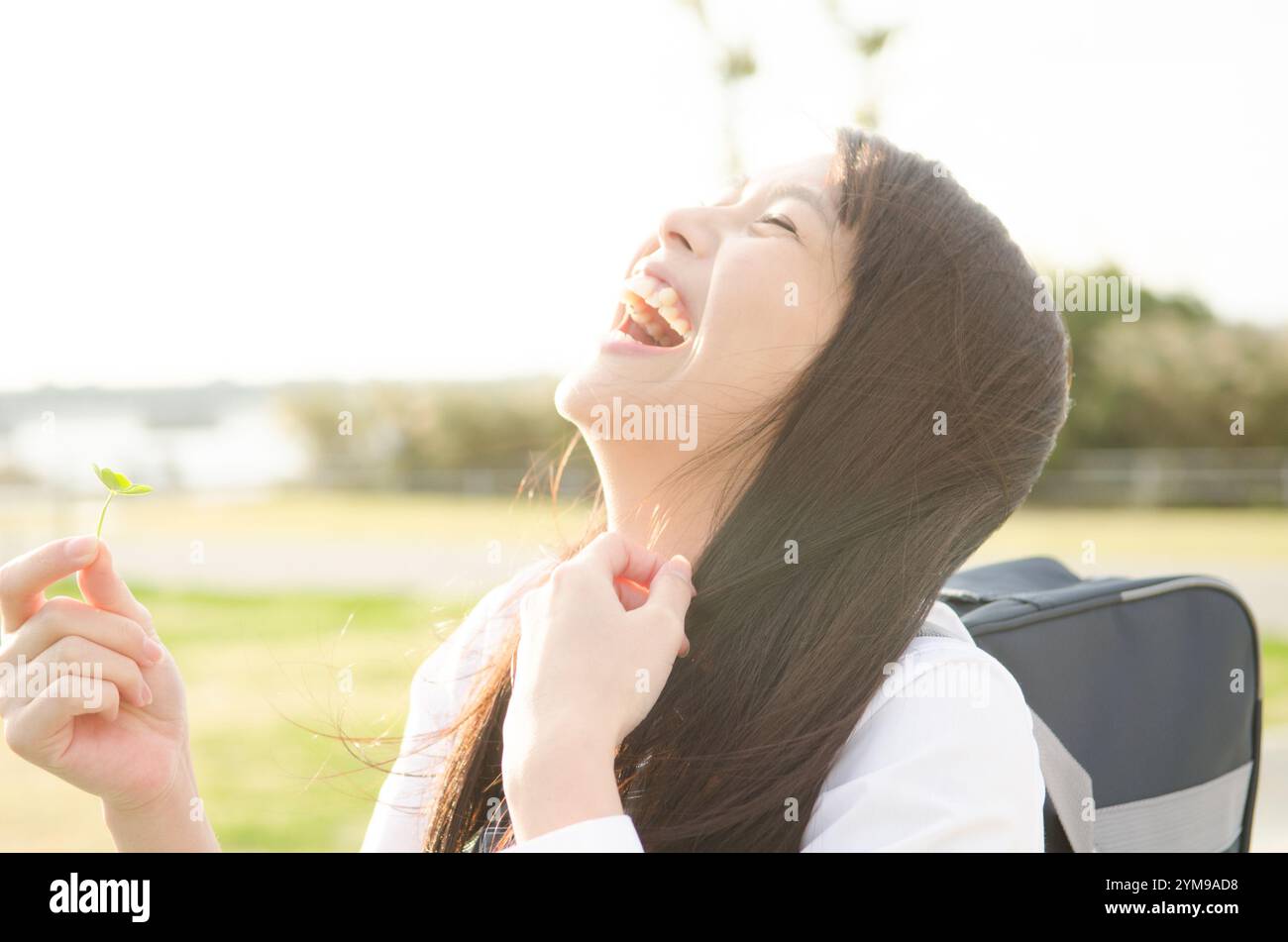 Female student laughing holding clover Stock Photo - Alamy