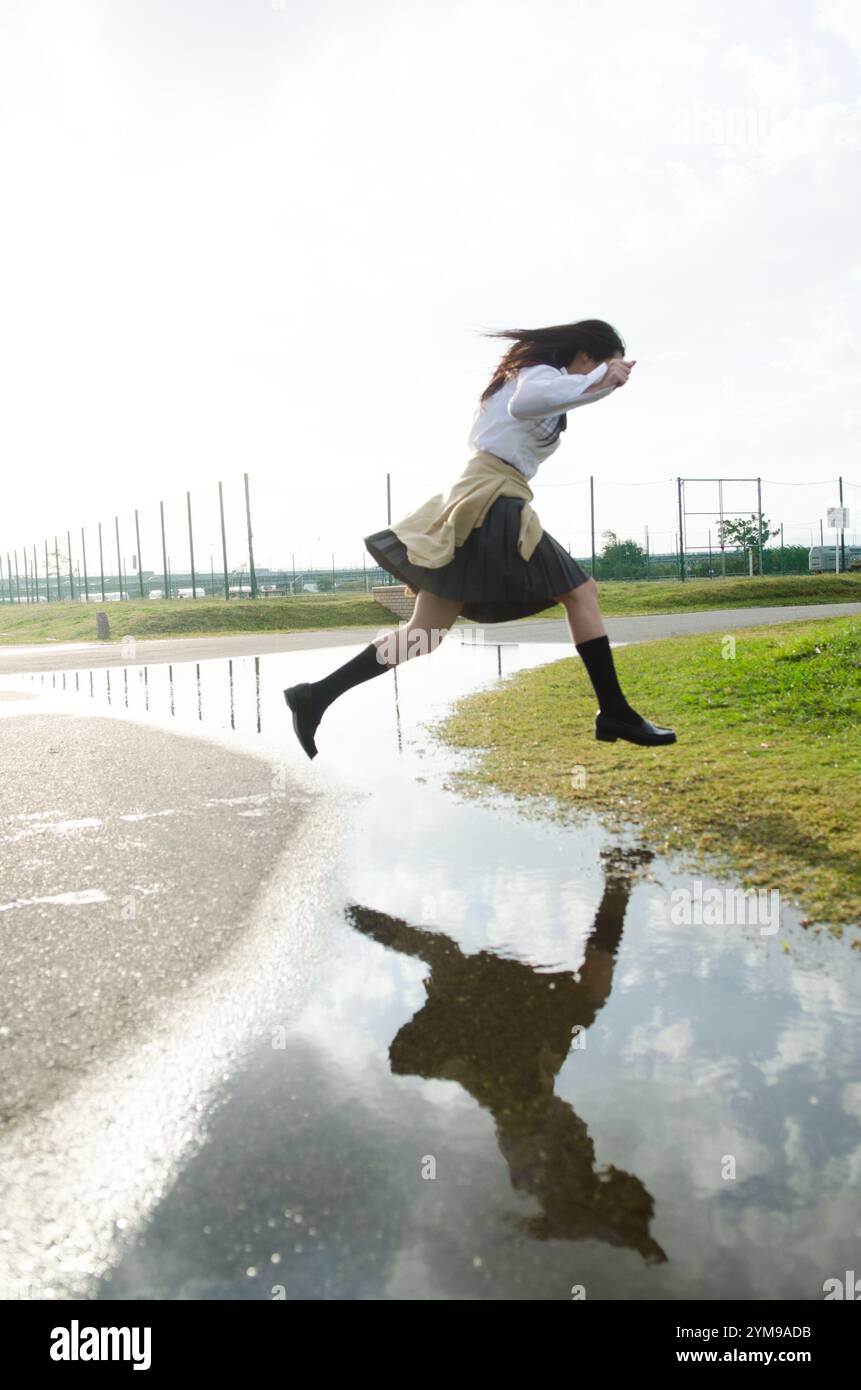 Schoolgirl jumping through puddle Stock Photo - Alamy