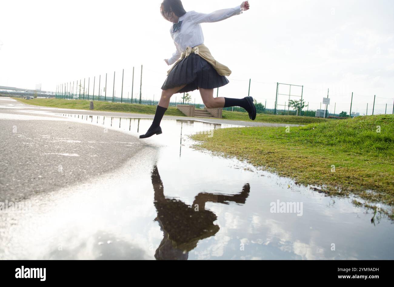 Schoolgirl jumping through puddle Stock Photo - Alamy