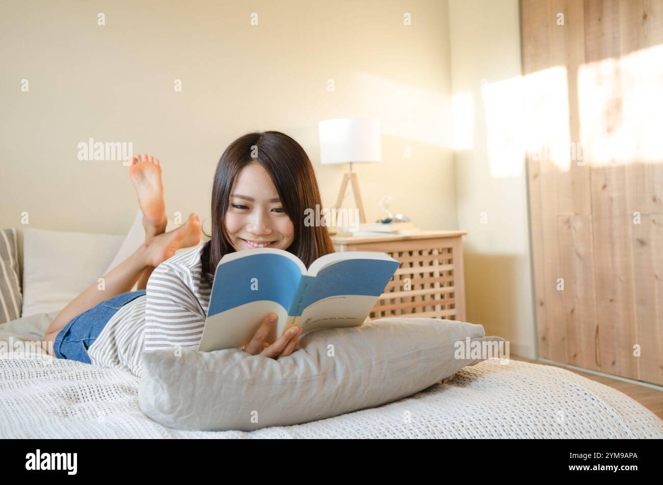 Woman reading book in bed Stock Photo - Alamy
