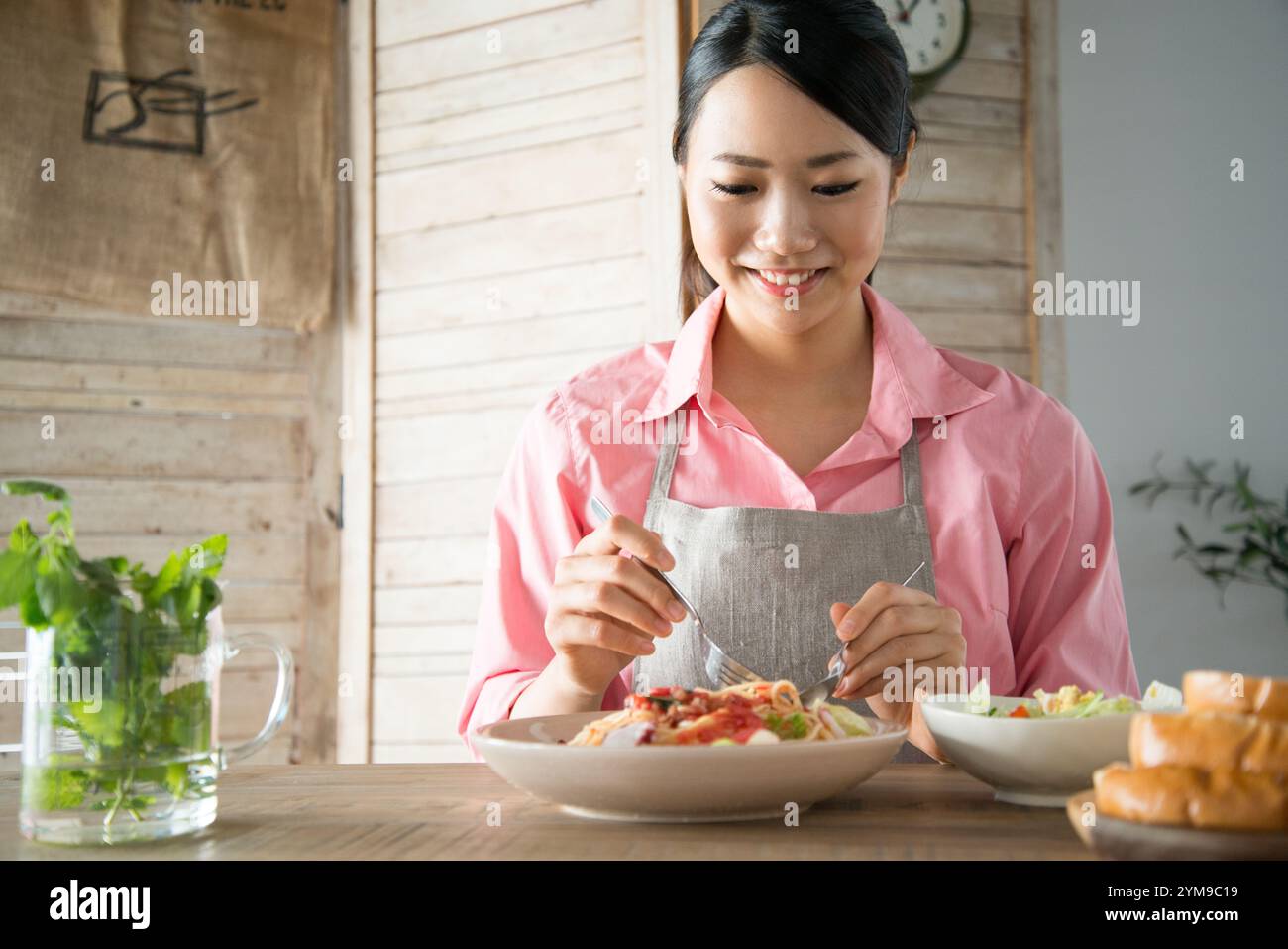 Woman with apron trying to eat pasta Stock Photo - Alamy