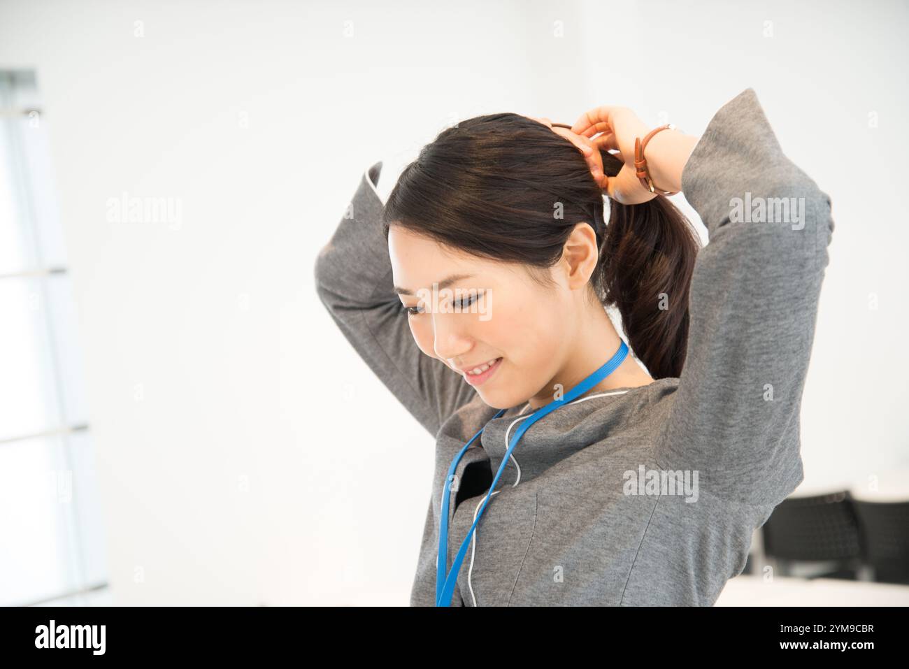 Woman tying her hair Stock Photo - Alamy