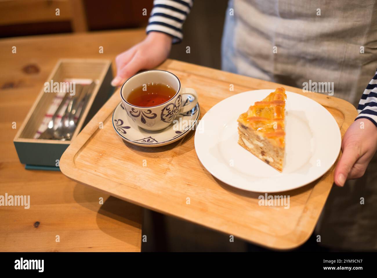 Woman's hand holding tray with cake and tea on it Stock Photo - Alamy