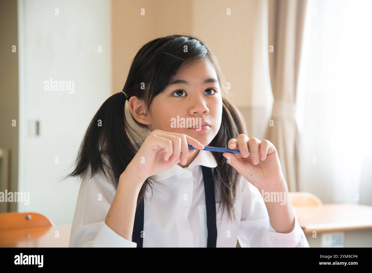 Primary school girl holding pencil Stock Photo - Alamy