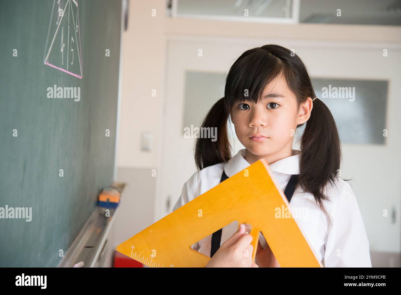 Primary schools girl standing in front of blackboard Stock Photo - Alamy