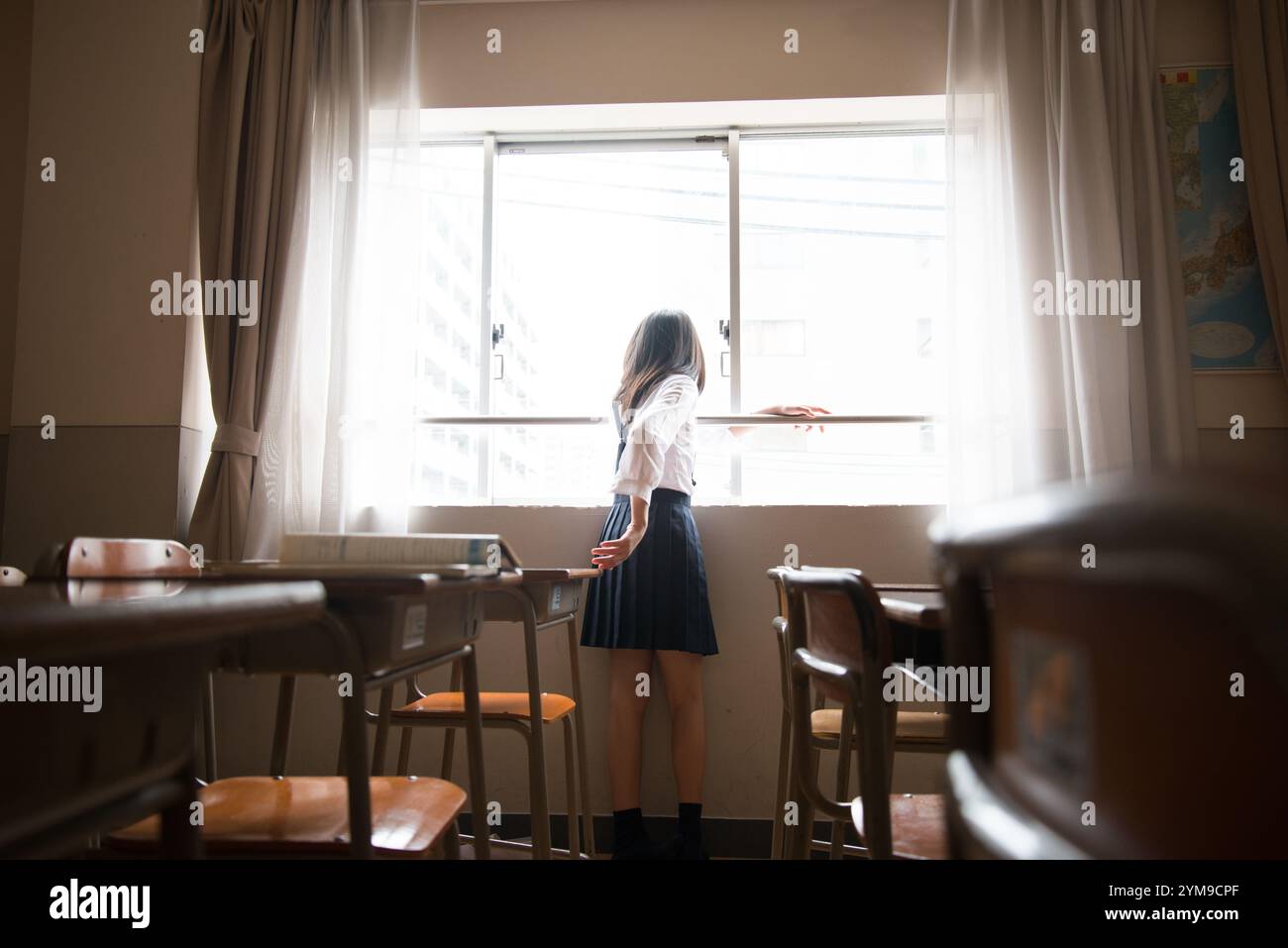 Primary school girl looking out of classroom window Stock Photo - Alamy