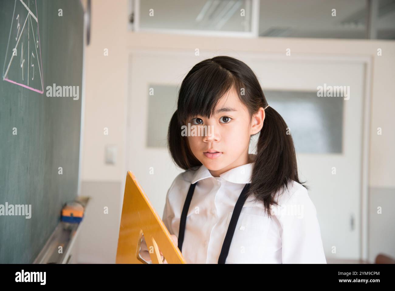 Primary schools girl standing in front of blackboard Stock Photo - Alamy
