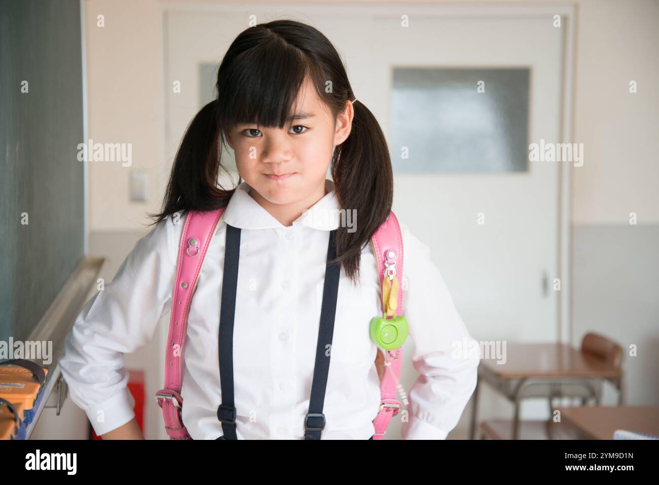 Primary schools girl carrying her school bag in the classroom Stock Photo - Alamy