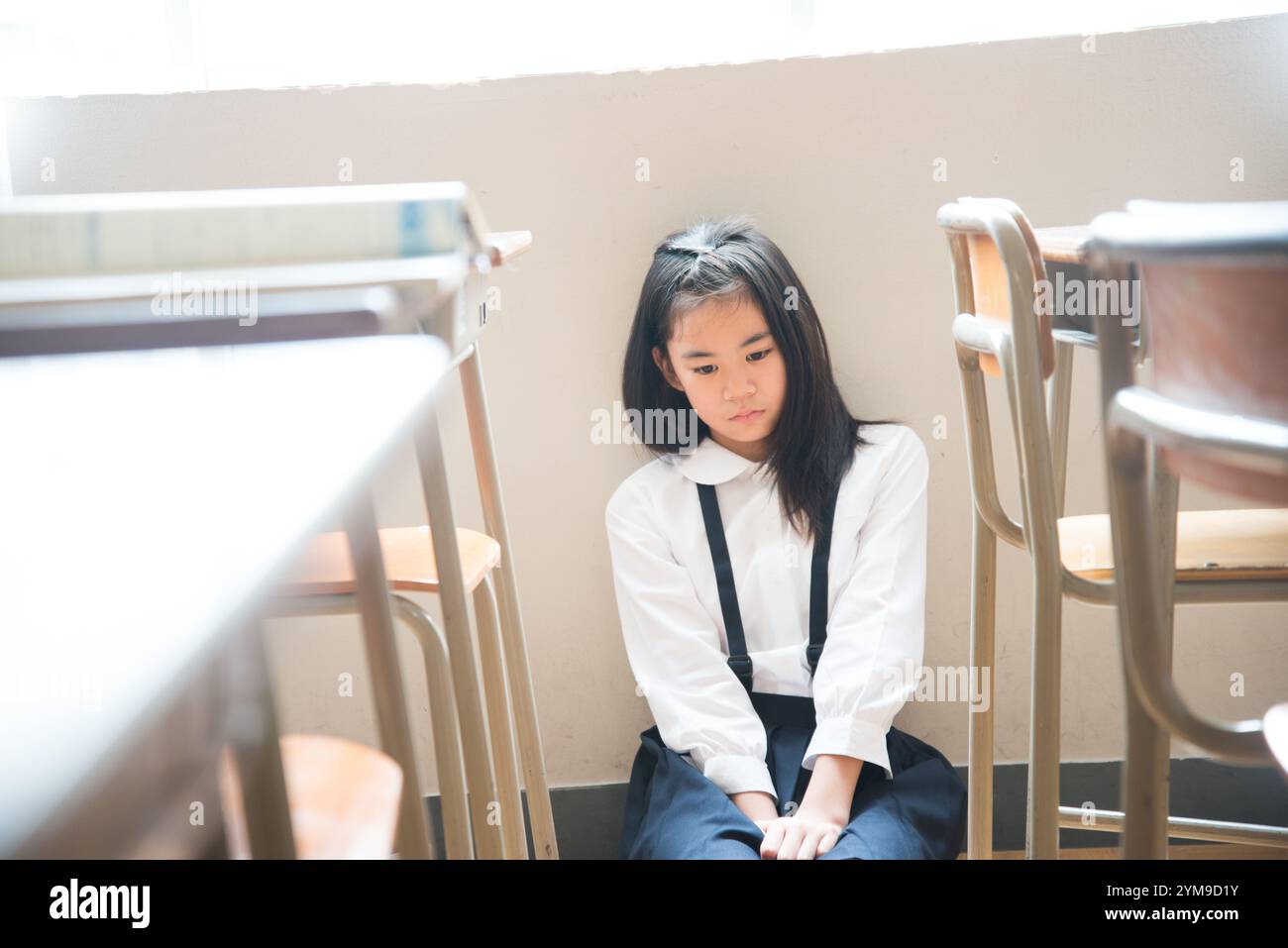 Primary school girl sitting on the floor of the classroom Stock Photo ...