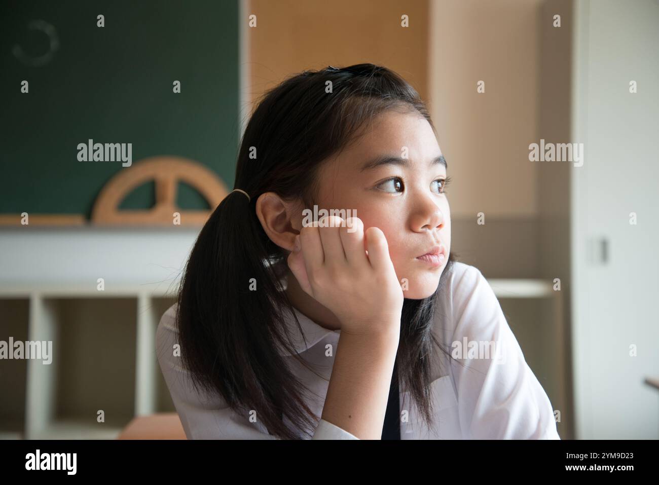 Primary school girl looking out in the classroom Stock Photo - Alamy