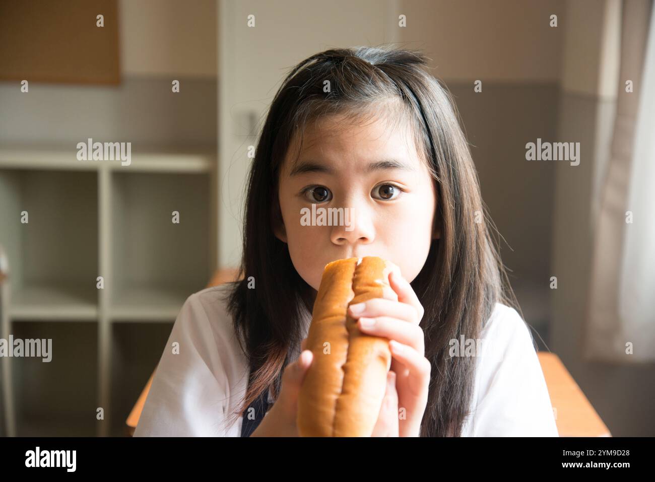Primary school girl eating a koppe bread Stock Photo - Alamy