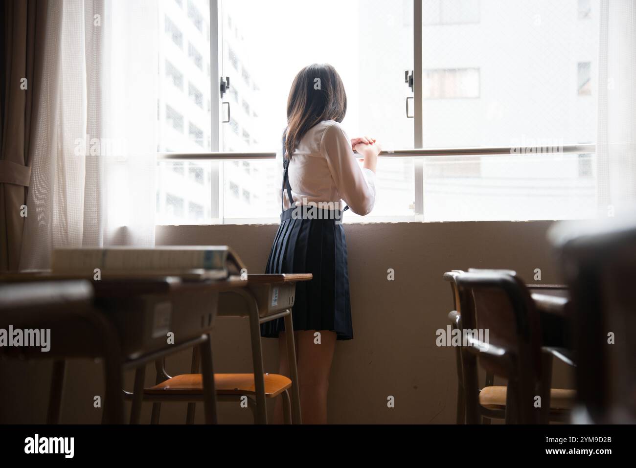 Primary school girl looking out of classroom window Stock Photo - Alamy