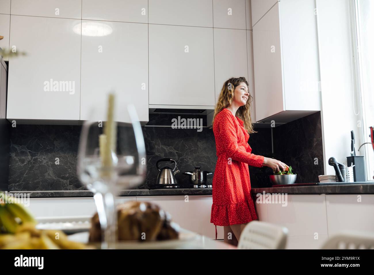 Woman in dress cooking a romantic dinner in the kitchen Stock Photo - Alamy