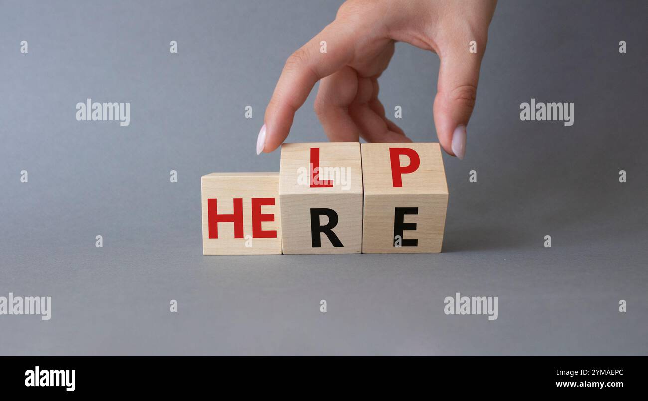 Help is here symbol. Businessman hand Turns cube and changes word Here ...