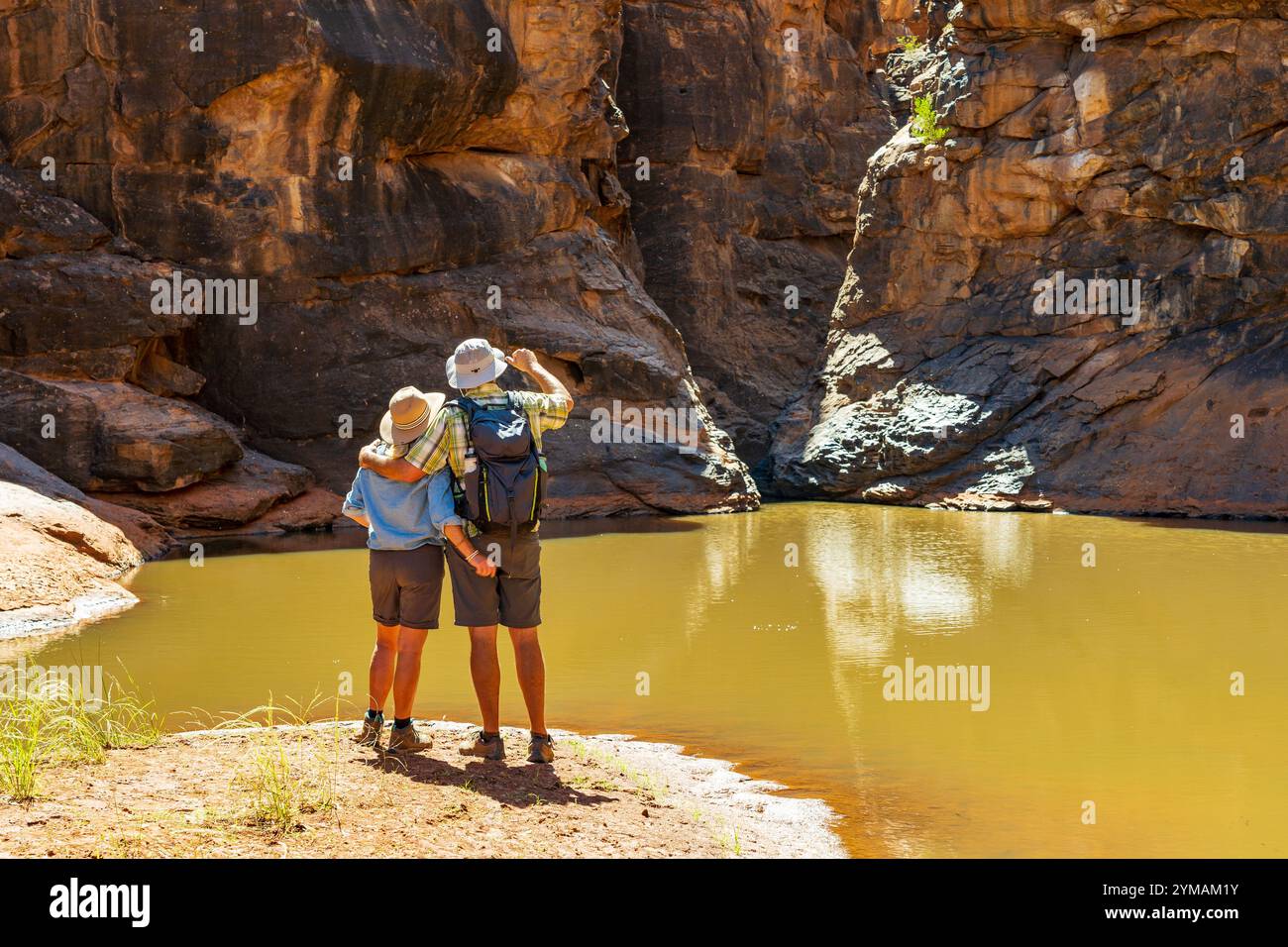 A couple standing on the edge of a waterfall admiring the view of a ...