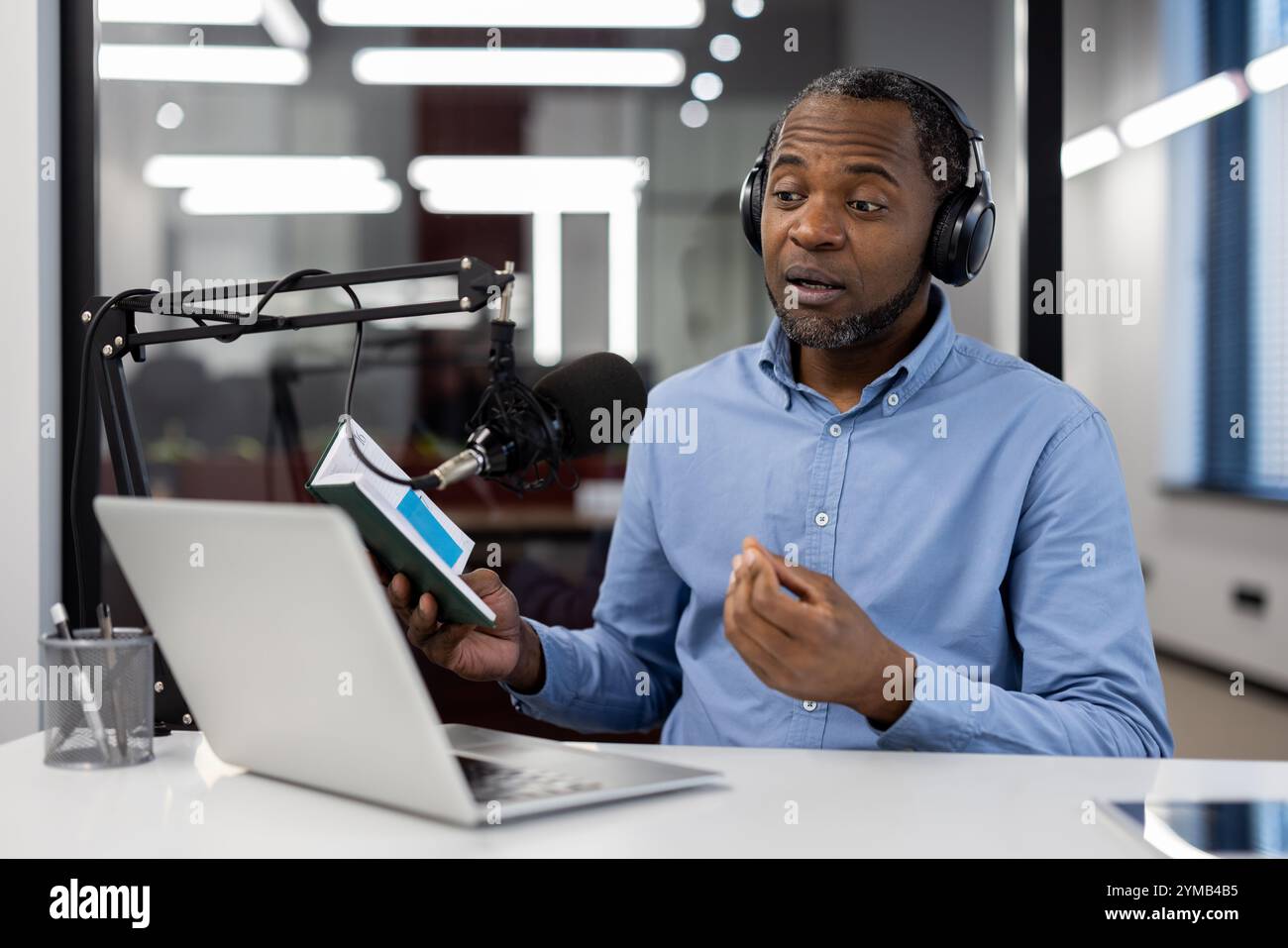 Mature African American businessman recording podcast in modern studio ...