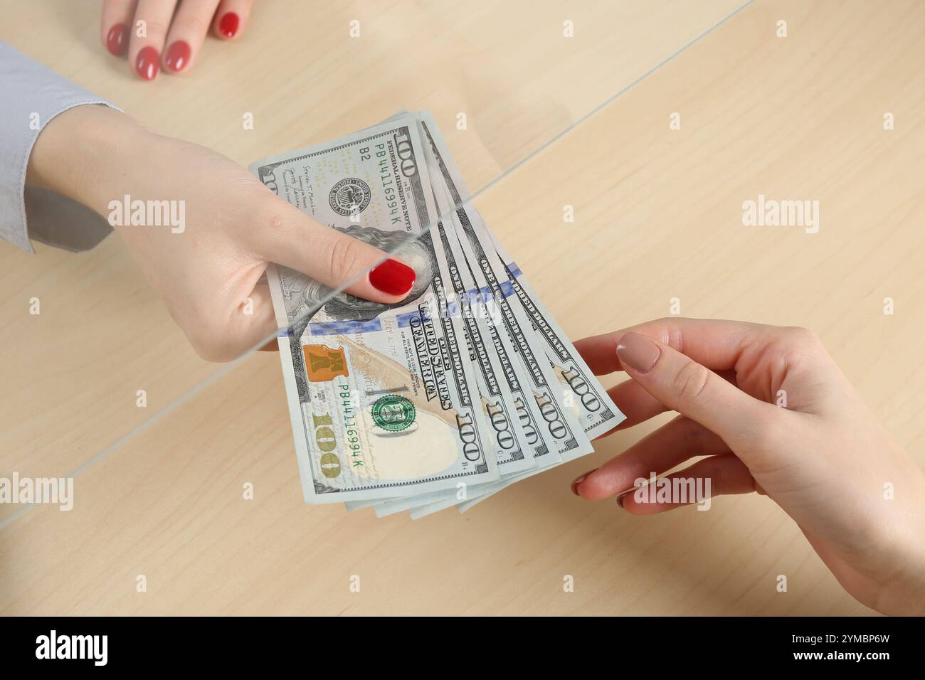 Cashier giving dollar banknotes to client at table in money exchange ...