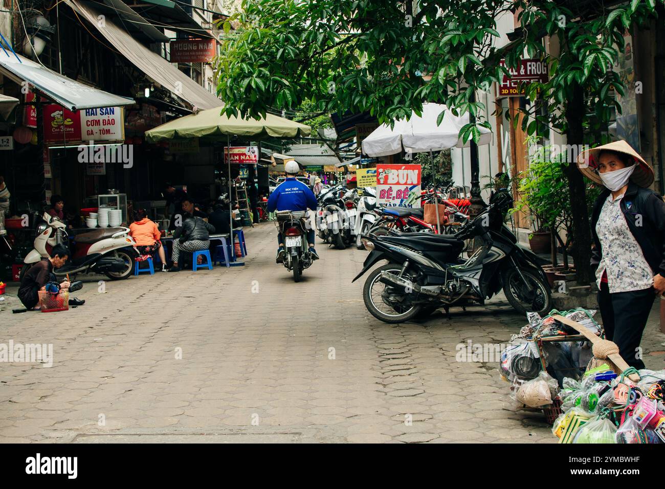 In the streets of Hanoi a Vietnamese street vendor woman wears a ...