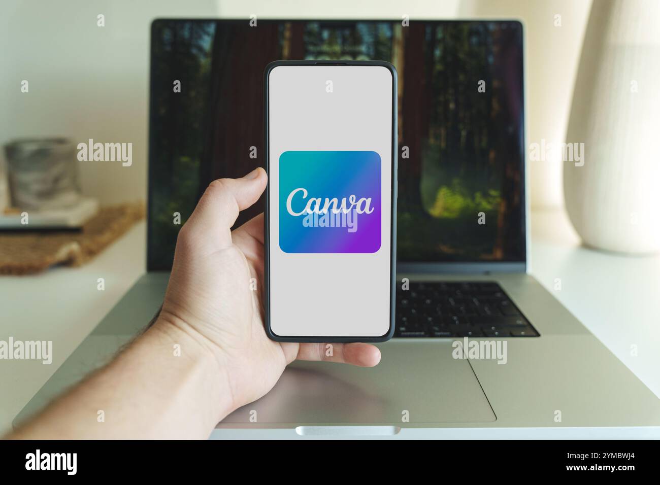 Canva design application logo on smartphone screen in front of laptop ...