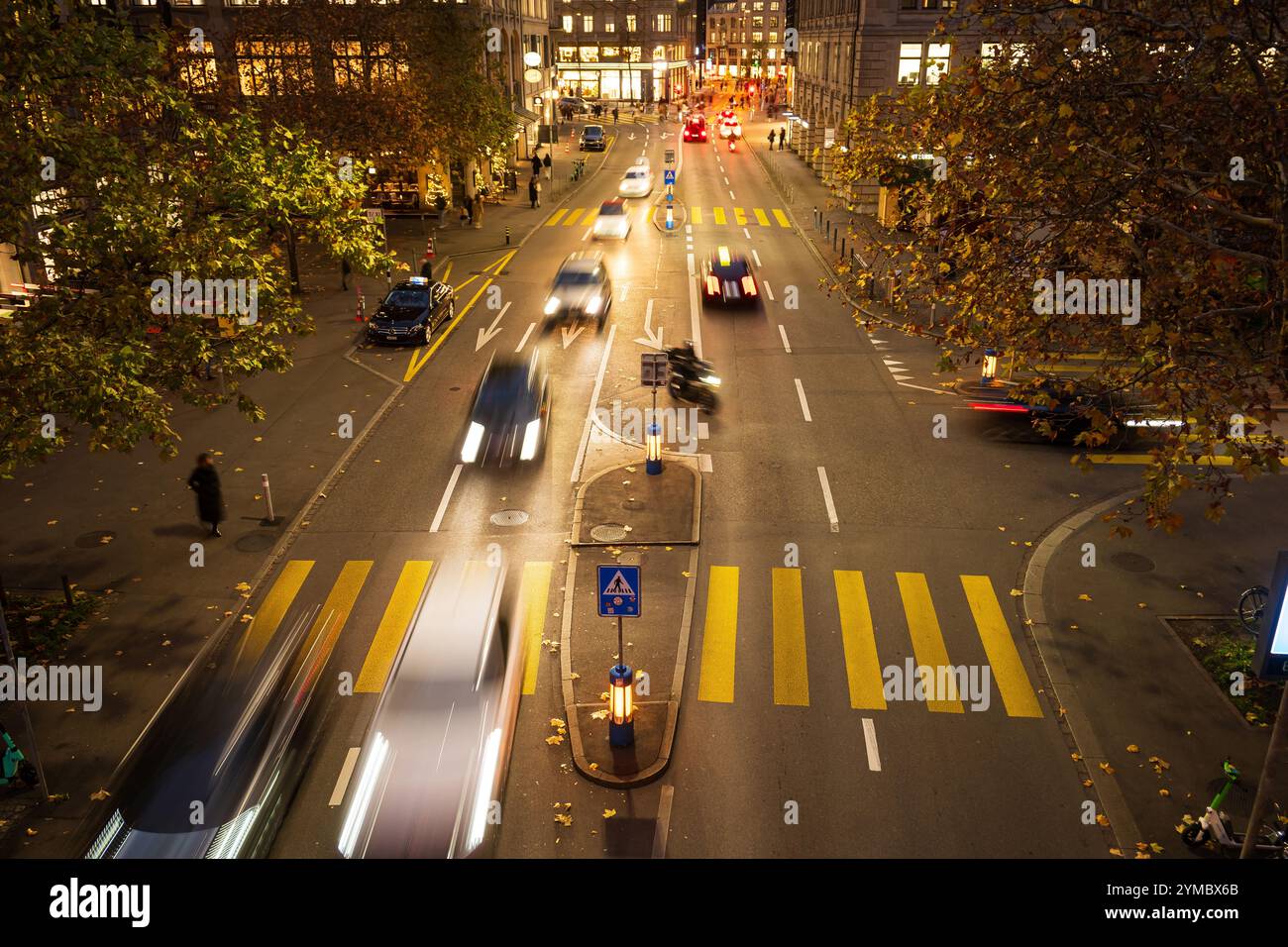 Car traffic on busy street with pedestrian crossing at night in a city ...