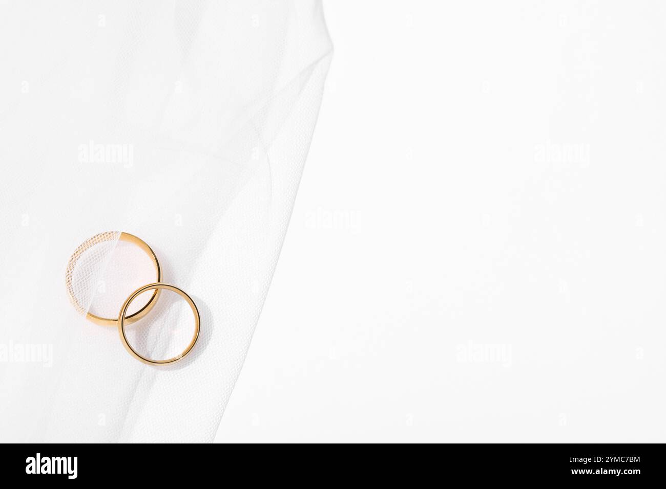 Golden wedding rings and veil on white background, top view. Space for ...