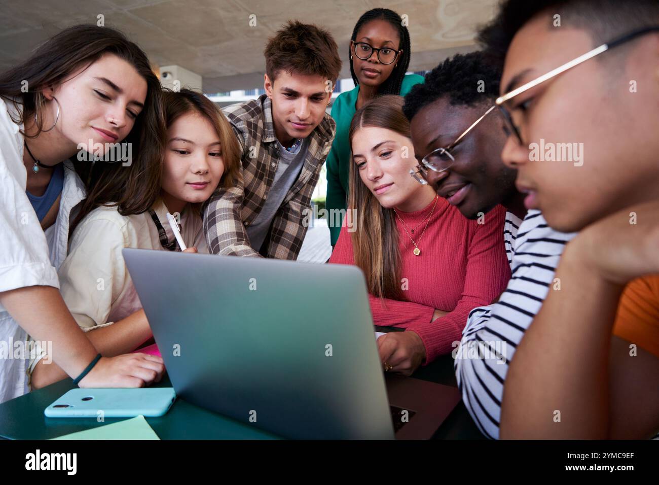 Multiracial group of students sitting on a table studying together and ...