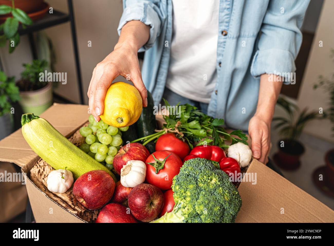 Unpacking a cardboard box with farm-grown organic fruits and vegetables ...