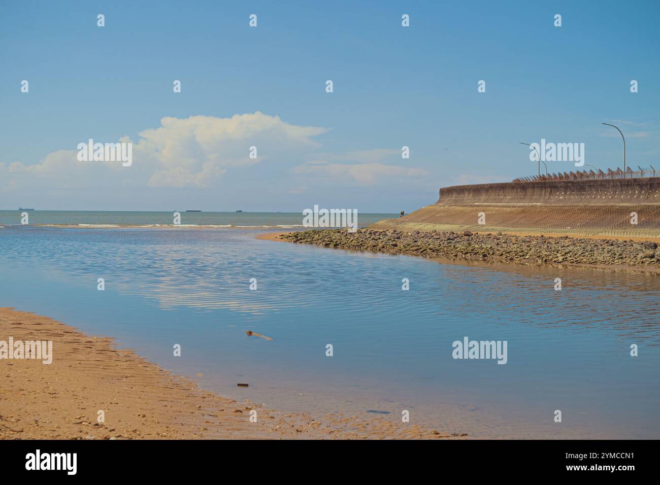The sea water is receding around the beach and dam, and a silhouette of ...