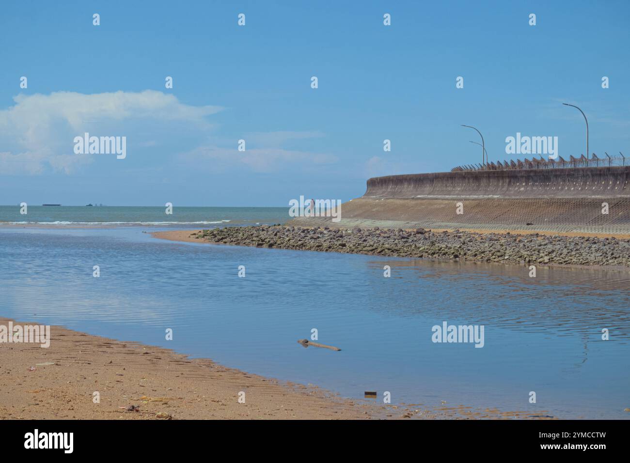 The sea water is receding around the beach and dam, and a silhouette of ...