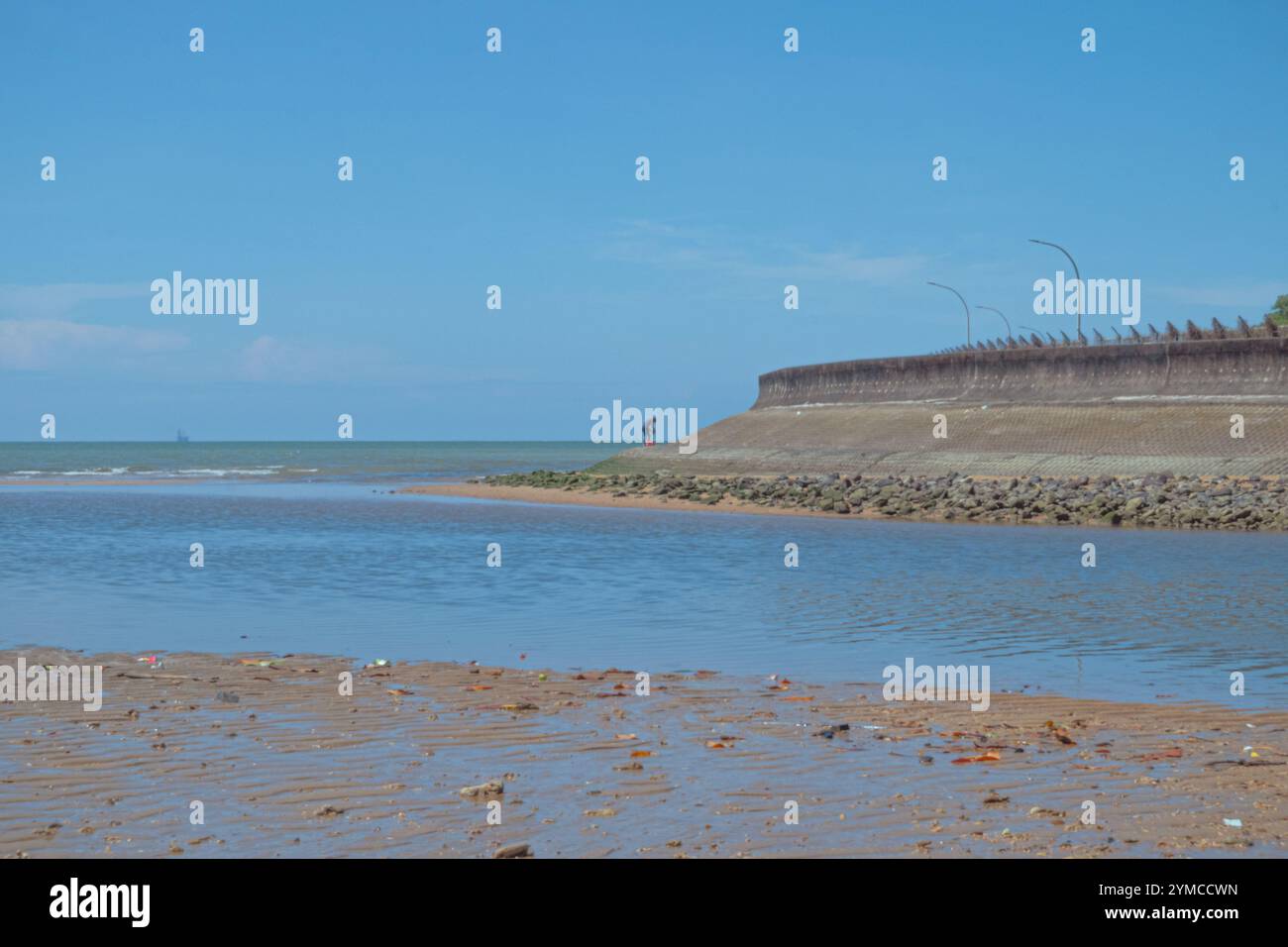 The sea water is receding around the beach and dam, and a silhouette of ...
