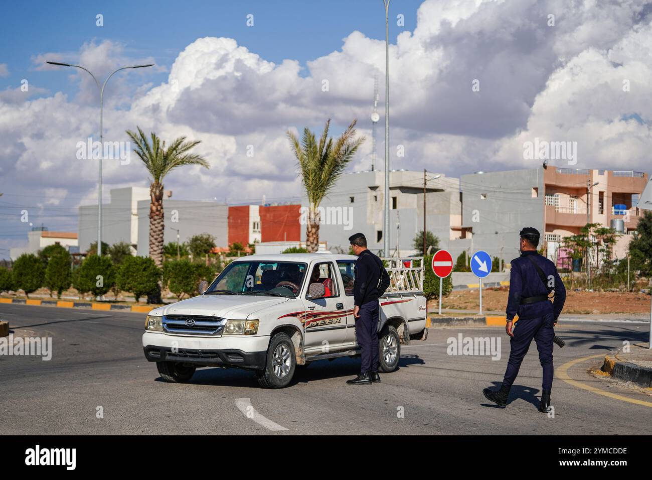 A member of the Iraqi security forces stop a car on an empty road in ...