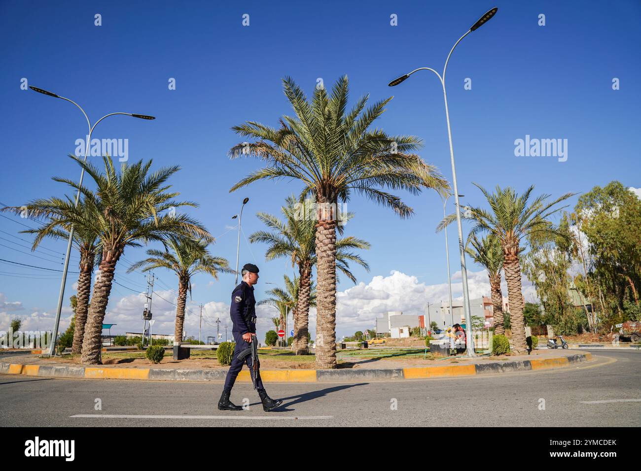 A member of the Iraqi security forces guard an empty road in the town ...