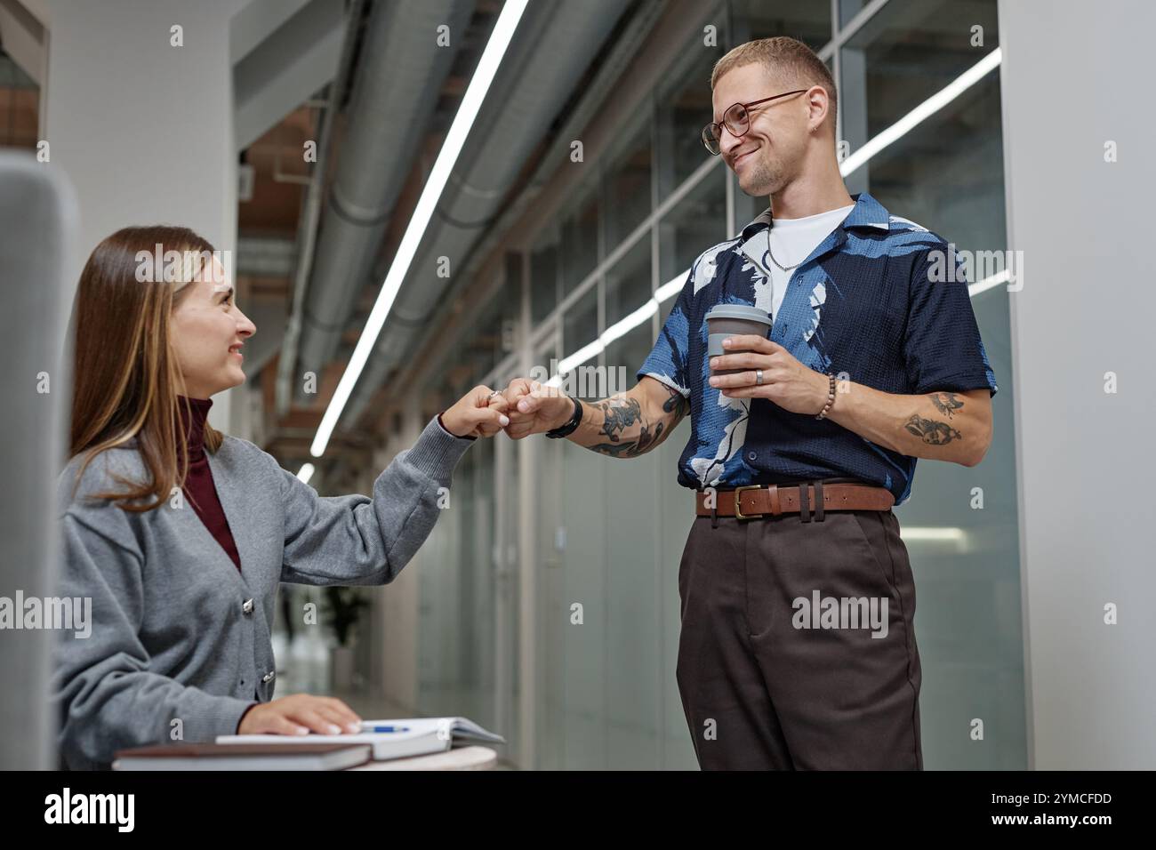 Side view of positive male businessman fist bumping with female ...