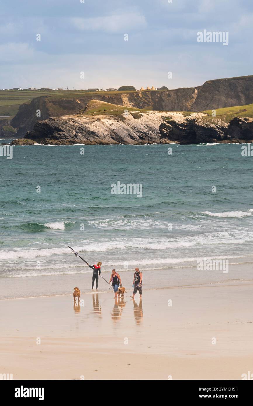 Holidaymakers walking along the shoreline of Towan Beach with the ...