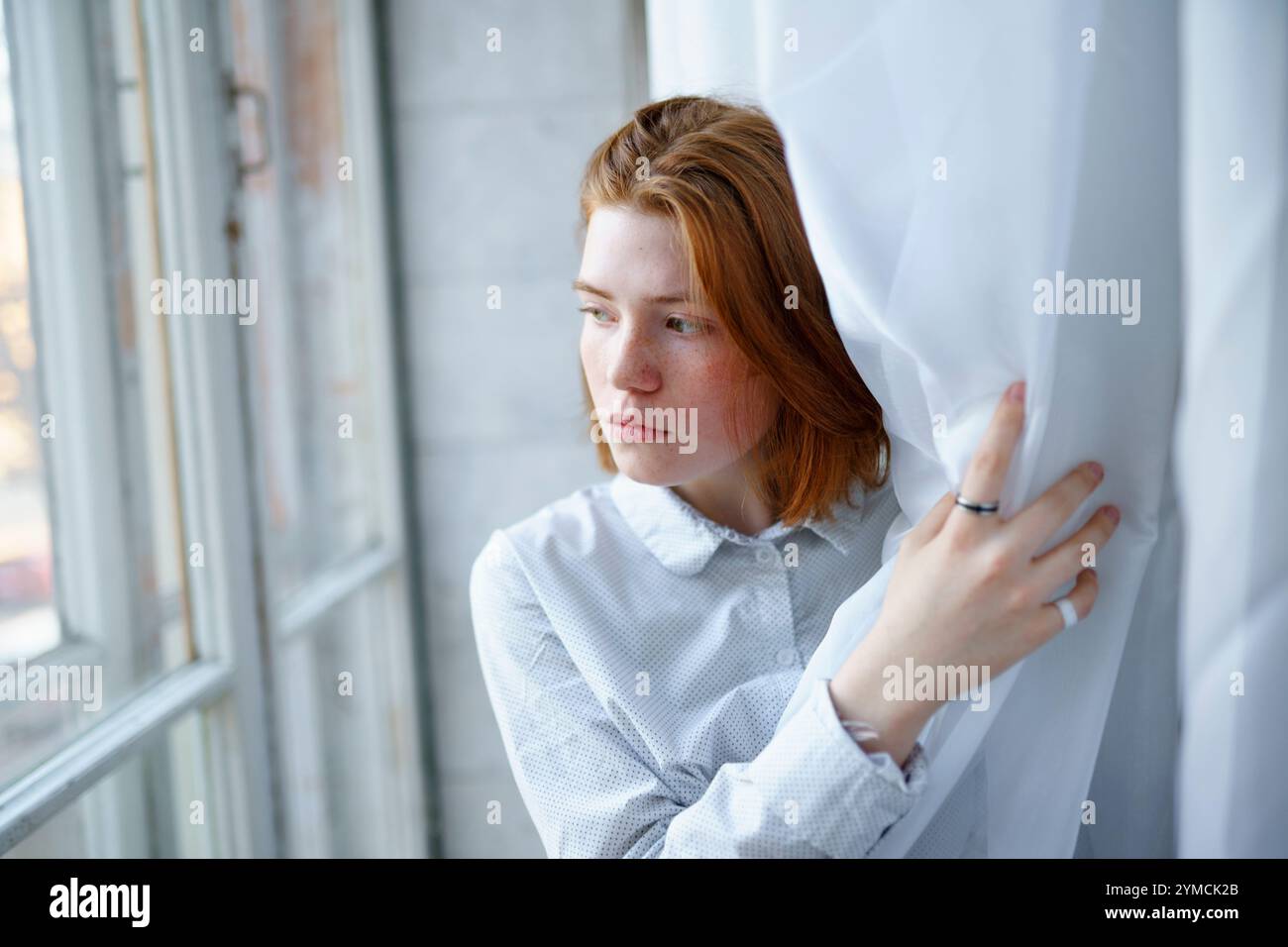Portrait of pensive woman looking through window Stock Photo - Alamy