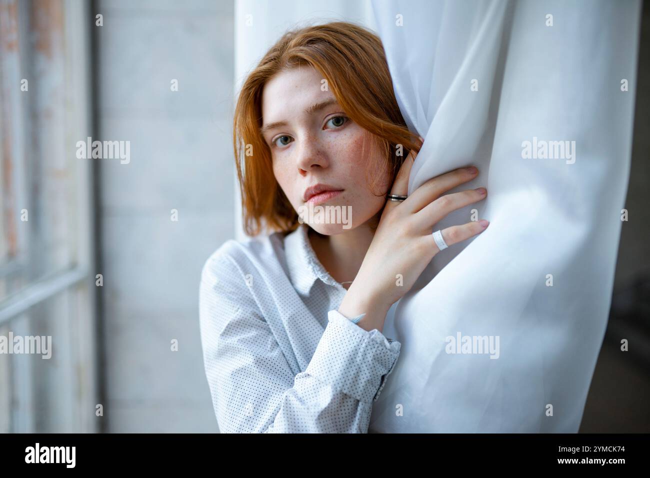 Portrait of pensive woman standing by window Stock Photo - Alamy