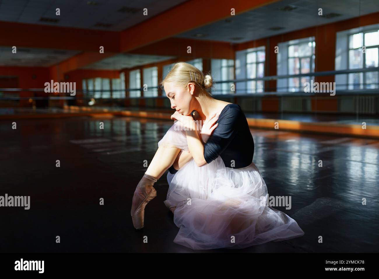 Pensive ballerina sitting on floor in ballet studio Stock Photo - Alamy