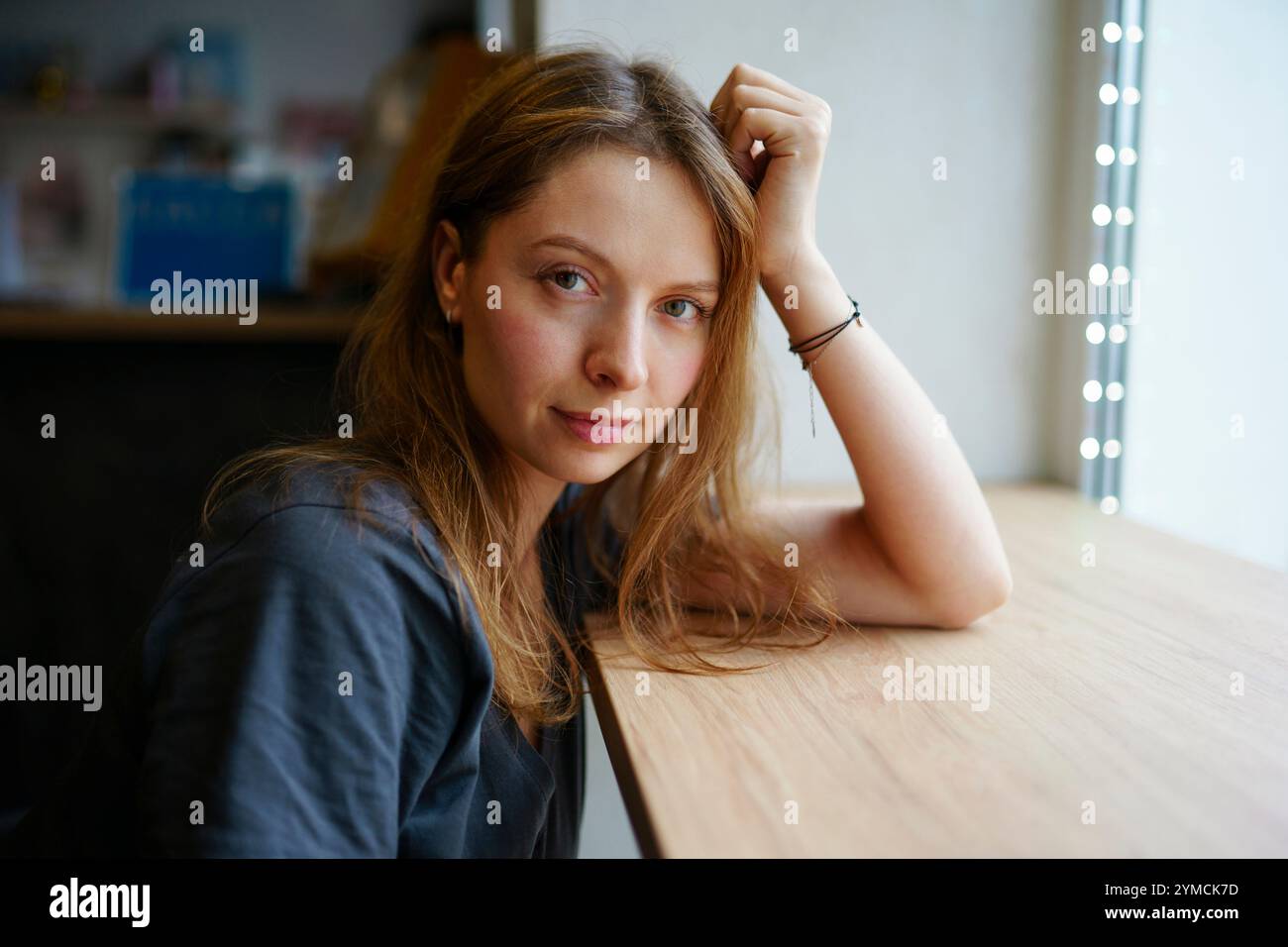 Portrait of woman leaning on window sill Stock Photo - Alamy